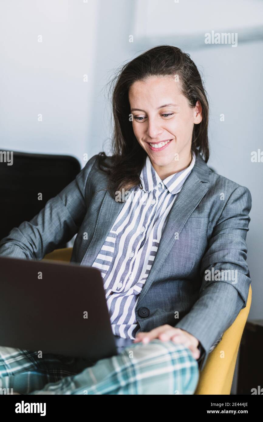 Young delighted female remote employee wearing formal blazer and homey ...