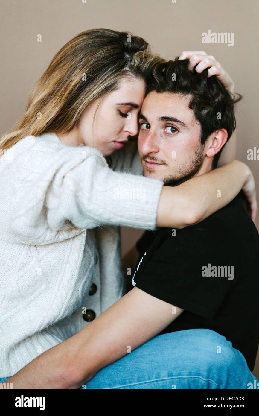 Side view of young couple cuddling with love in studio on beige ...