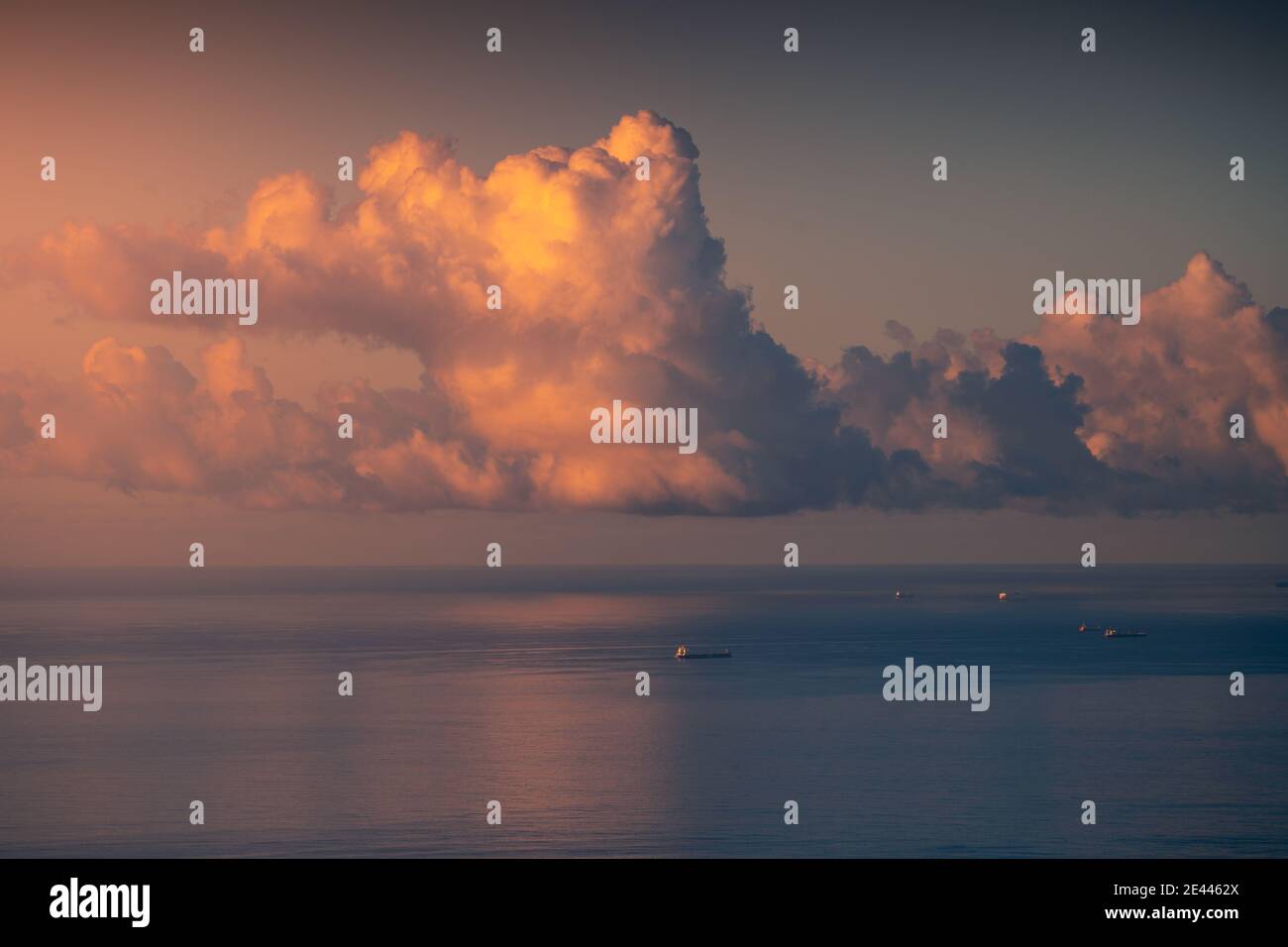 Boats floating in calm sea under sky with clouds illuminated by sunset ...