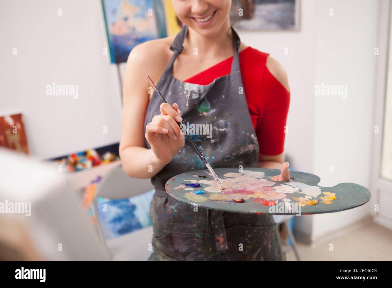 Cropped shot of a happy female artist smiling while mixing paint on her ...