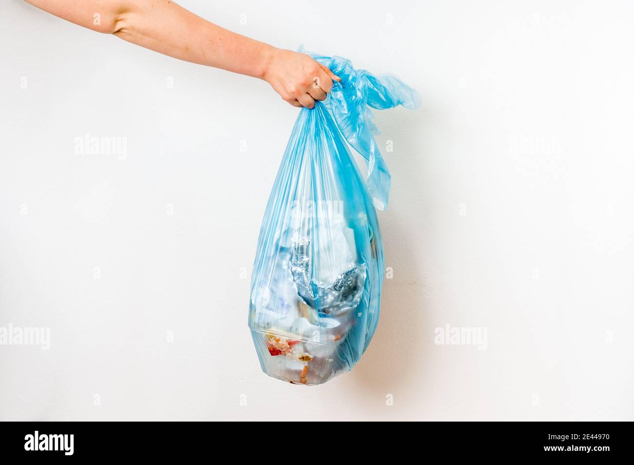Female hand holding blue garbage bag isolated on white background Stock ...