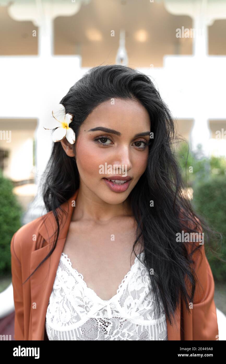 Young ethnic female model wearing stylish brown suit with flower in ...