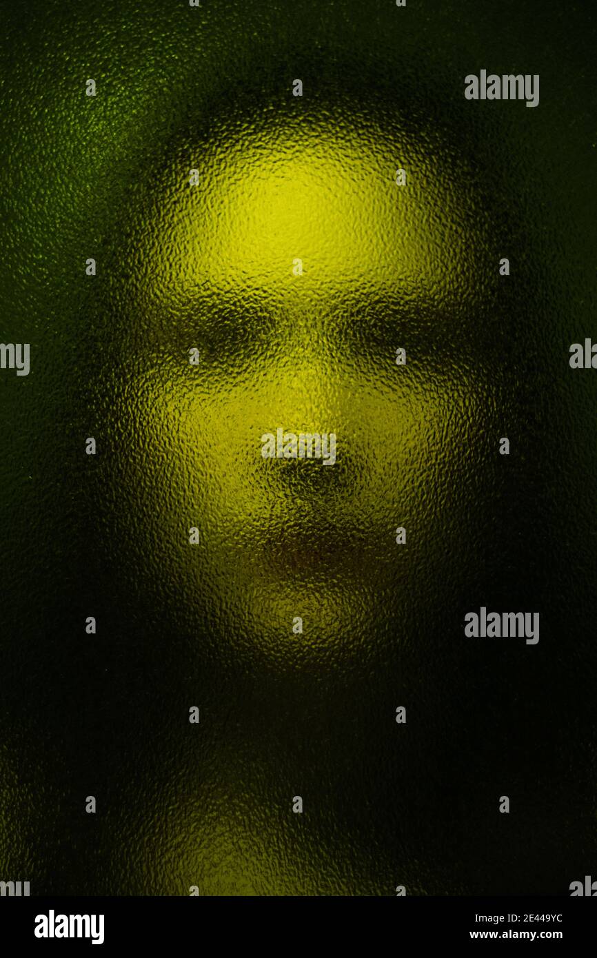 Headshot of anonymous person standing in room with dim green light and ...