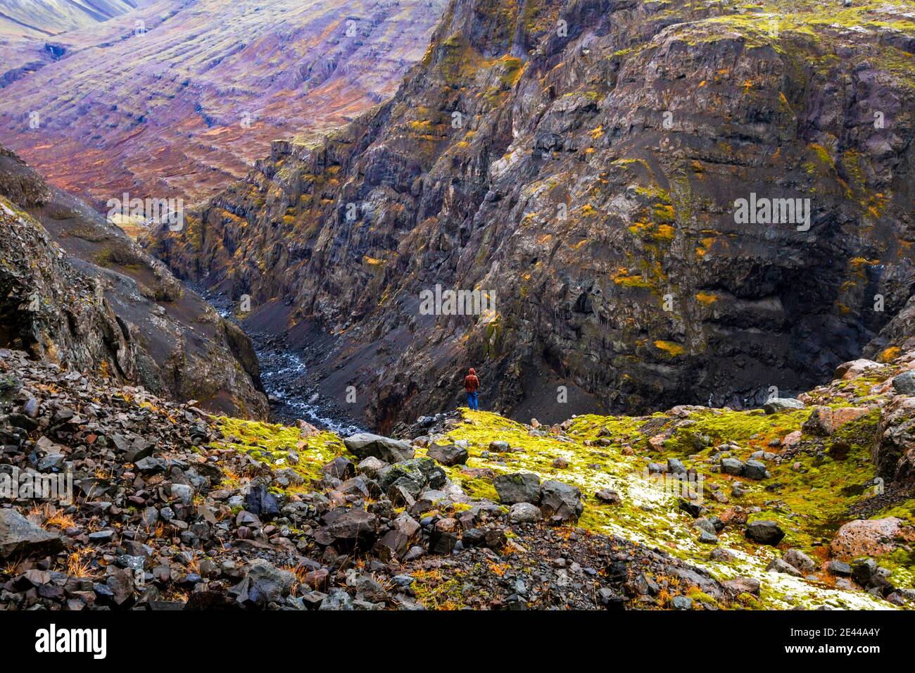 Remote view of explorer standing on rock and enjoying majestic ...