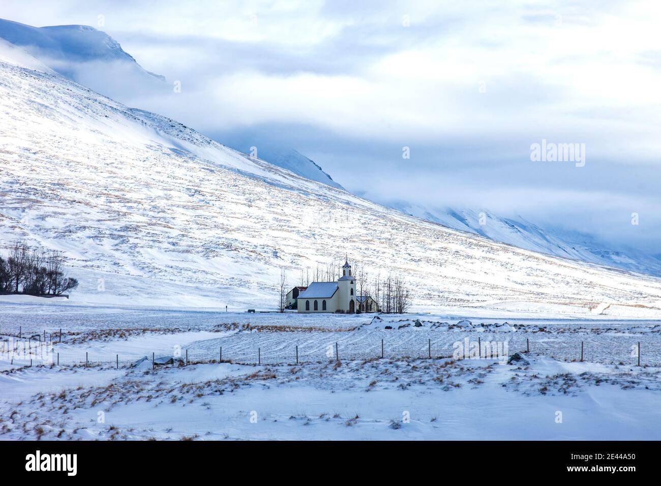 Lonely church located in mountains covered with snow in winter on sunny ...