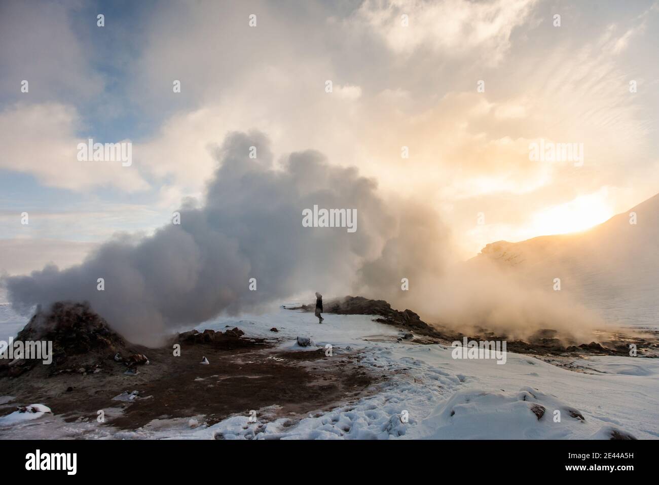 Unrecognizable explorer walking in highlands in winter near fuming ...