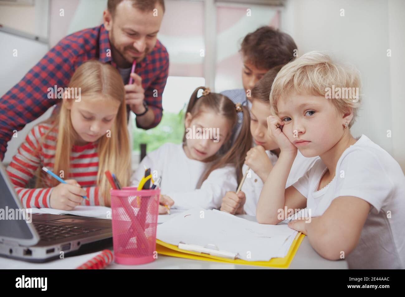 Little cute girl looking bored at class with her teacher and friends at ...