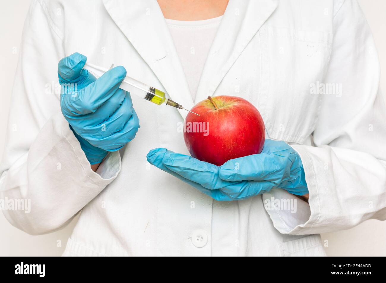 GMO scientist injecting liquid from syringe into apple - genetically ...