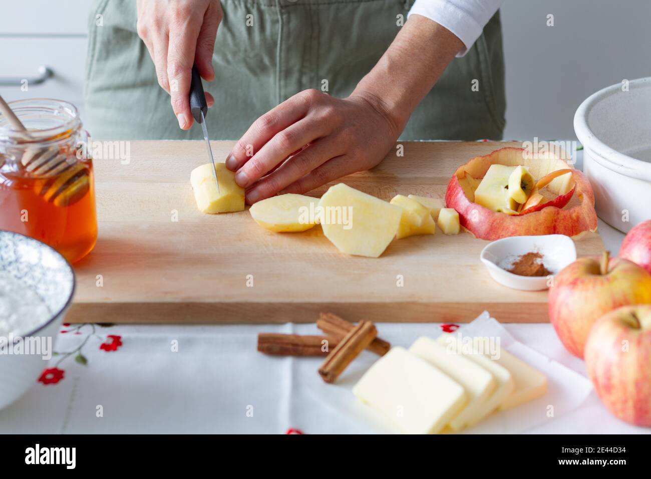 Unrecognizable person slicing peeled apple on cutting board near honey ...