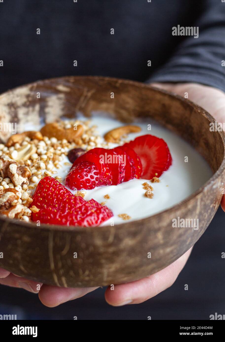 Closeup of crop anonymous person with bowl of yoghurt and granola with ...