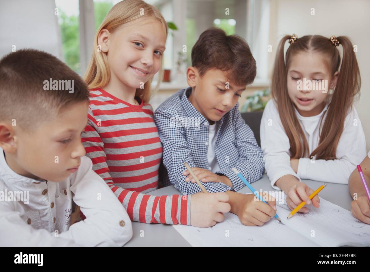 Happy young girl enjoying studying at art class with her classmates ...