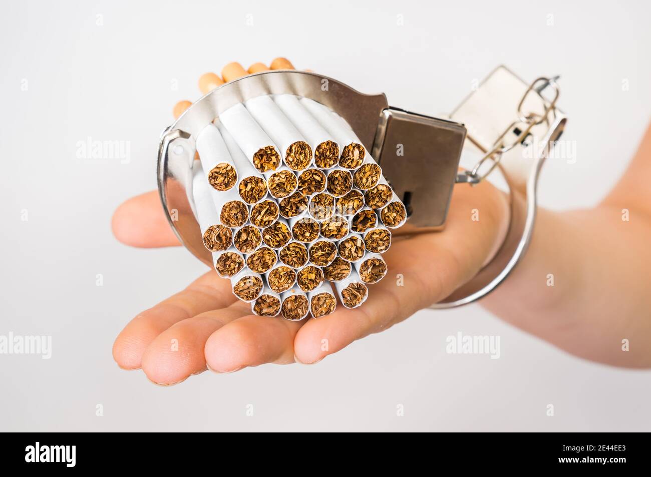 Female hand with handcuffs and cigarettes on white background - concept ...