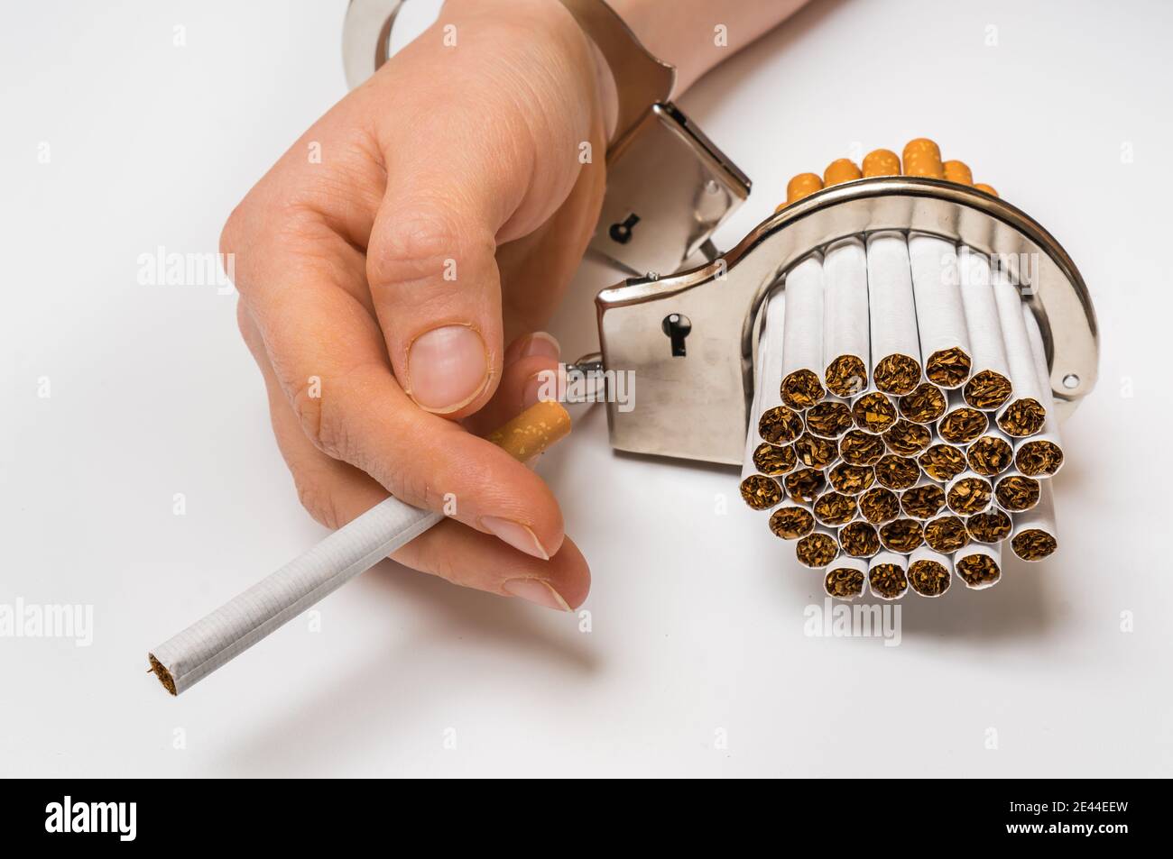 Female hand with handcuffs and cigarettes on white background - concept ...