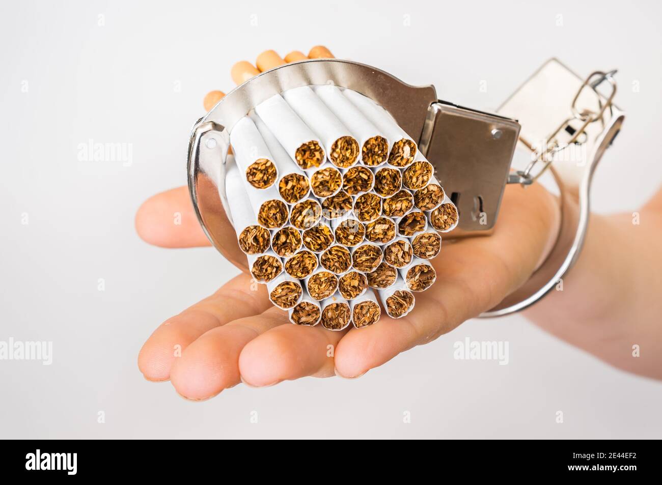 Female hand with handcuffs and cigarettes on white background - concept ...