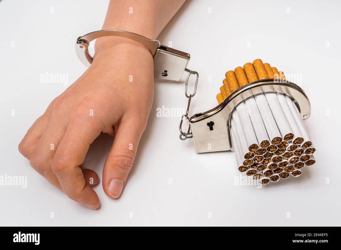 Female hand with handcuffs and cigarettes on white background - concept ...