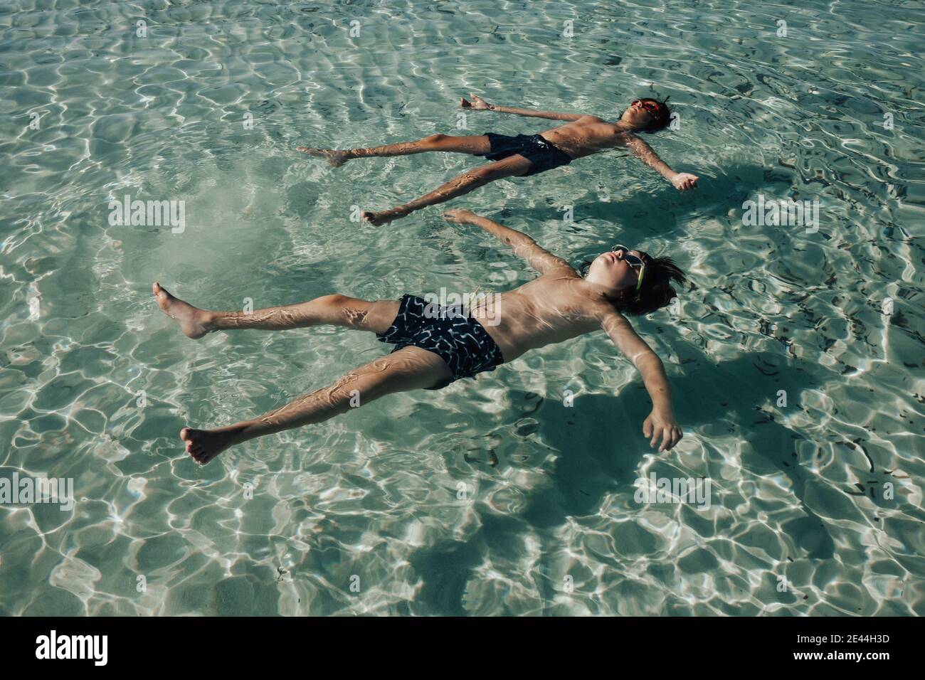 Two boys relaxed on the beach in summer while floating on the sea water ...