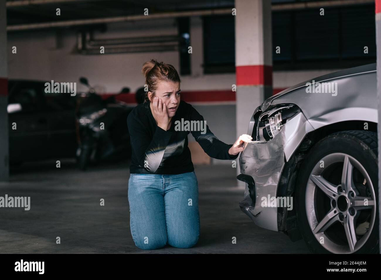 Upset young lady in casual clothes sitting on knees and touching ...
