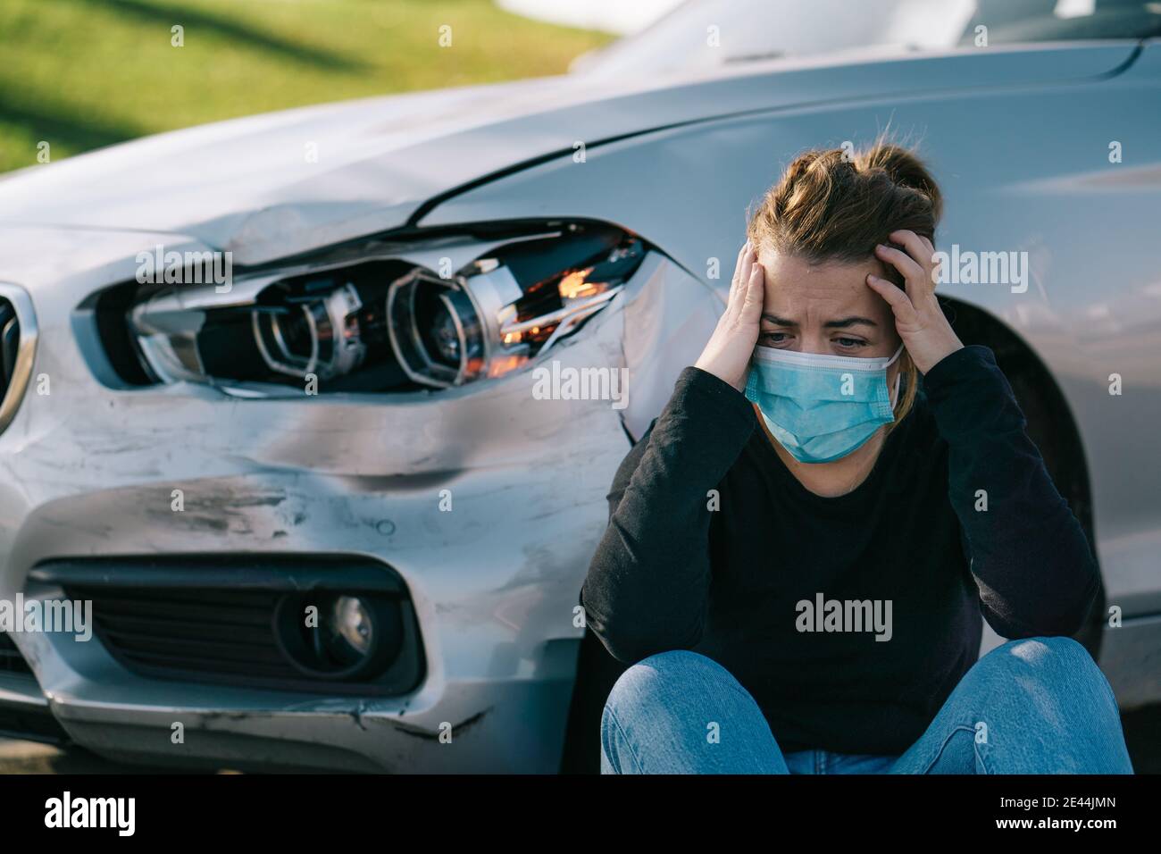 Sad young female driver in casual clothes and medical mask sitting on ...