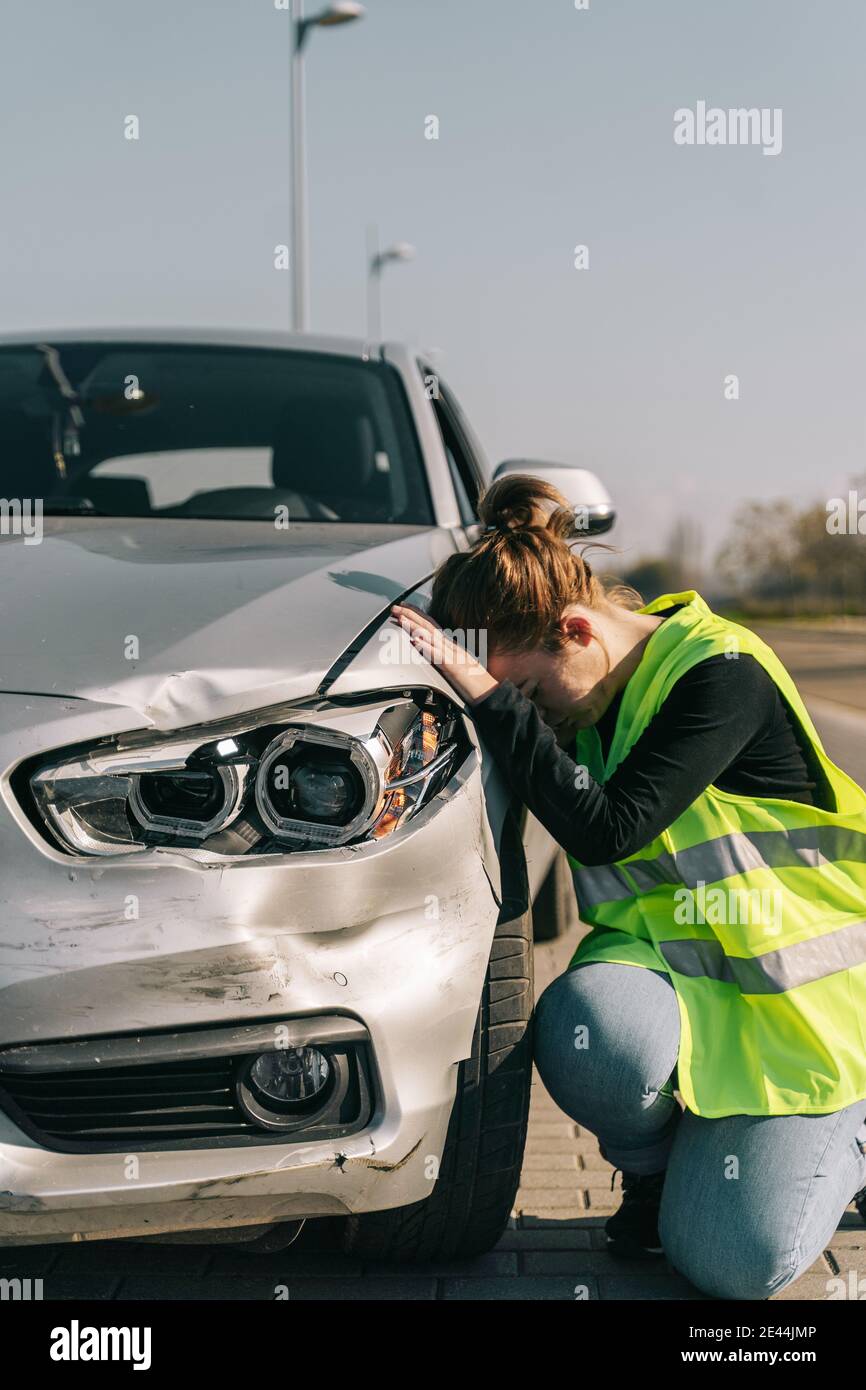 Side view of suffered young female driver in casual clothes and road ...