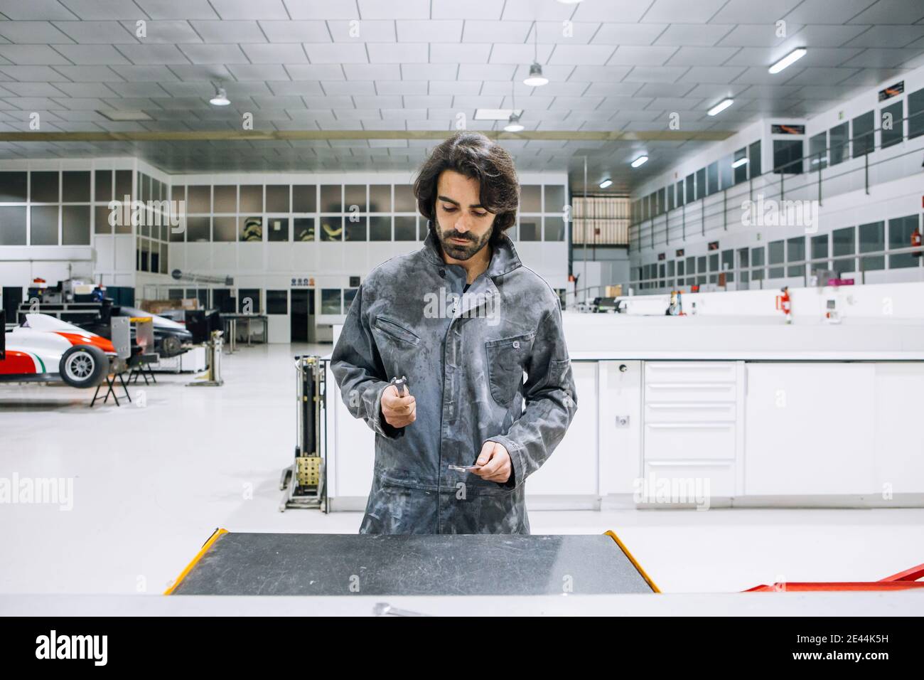 Busy male technician in dirty uniform standing near tool cabinet and ...