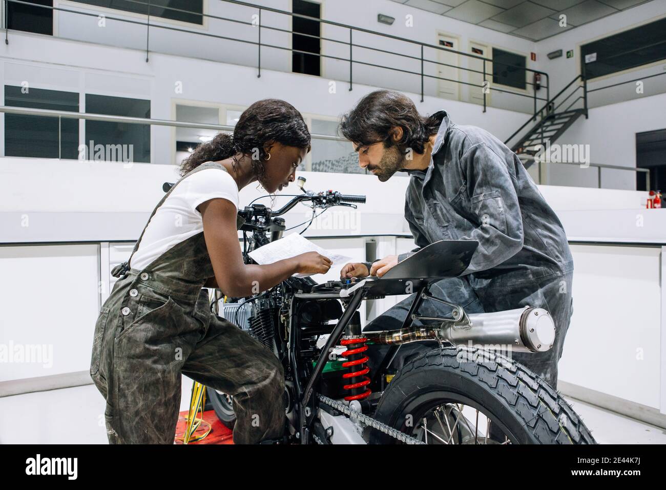 Side view of multiracial male and female mechanics repairing custom ...