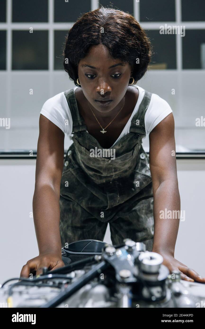 Serious young African American female mechanic assembling custom ...