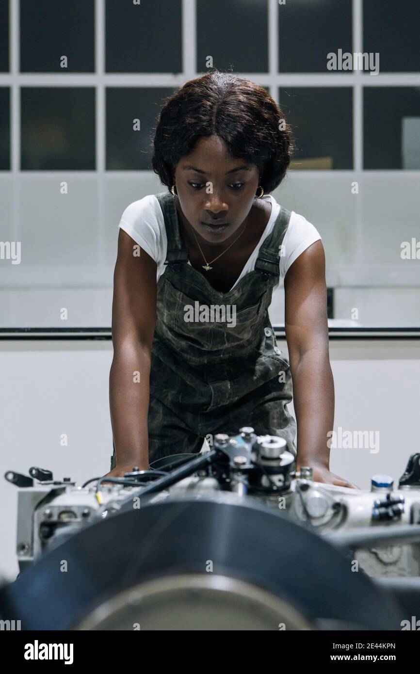 Serious young African American female mechanic assembling custom ...