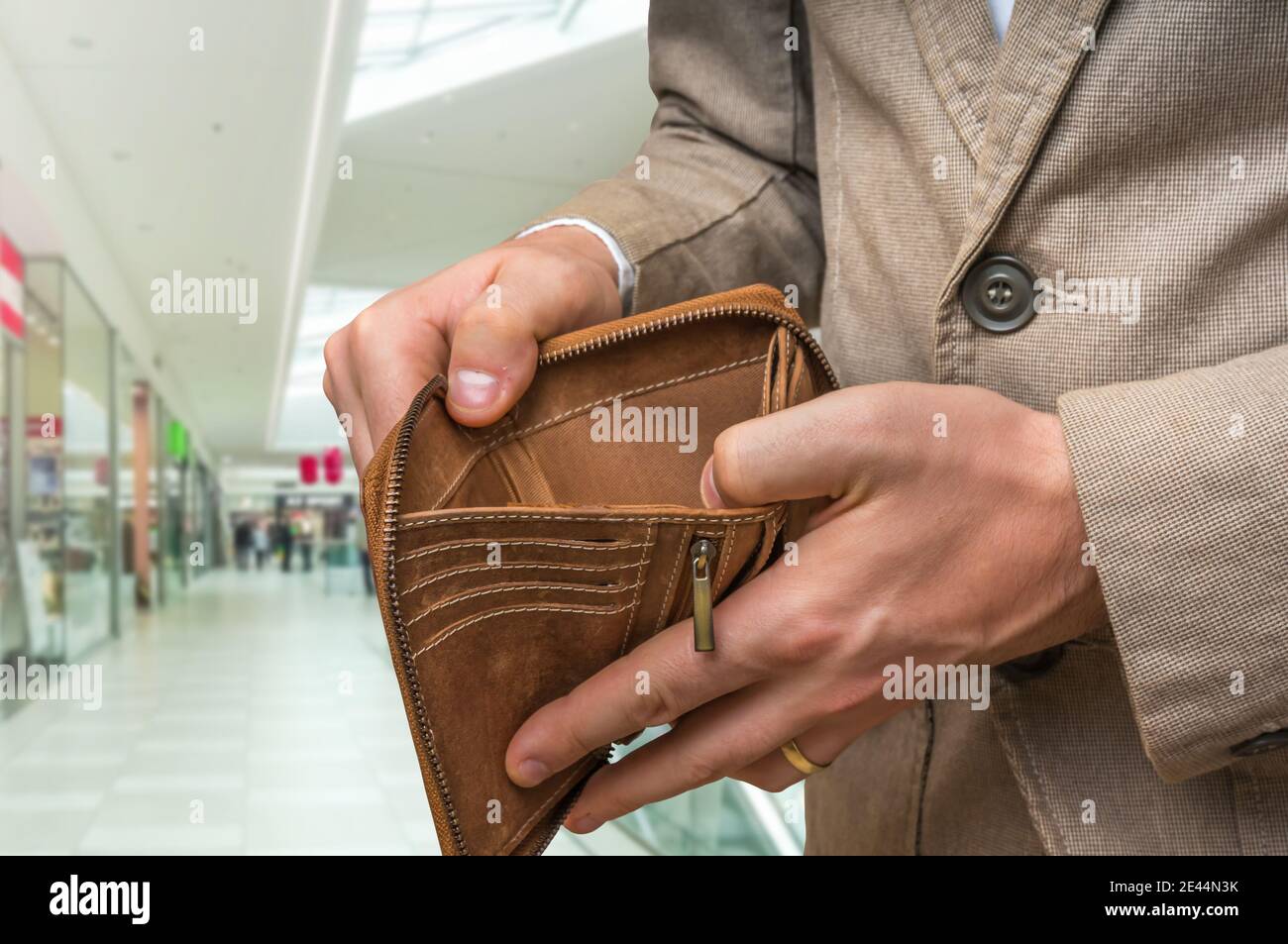Businessman holding an empty wallet in shopping centre, he hasn't money ...