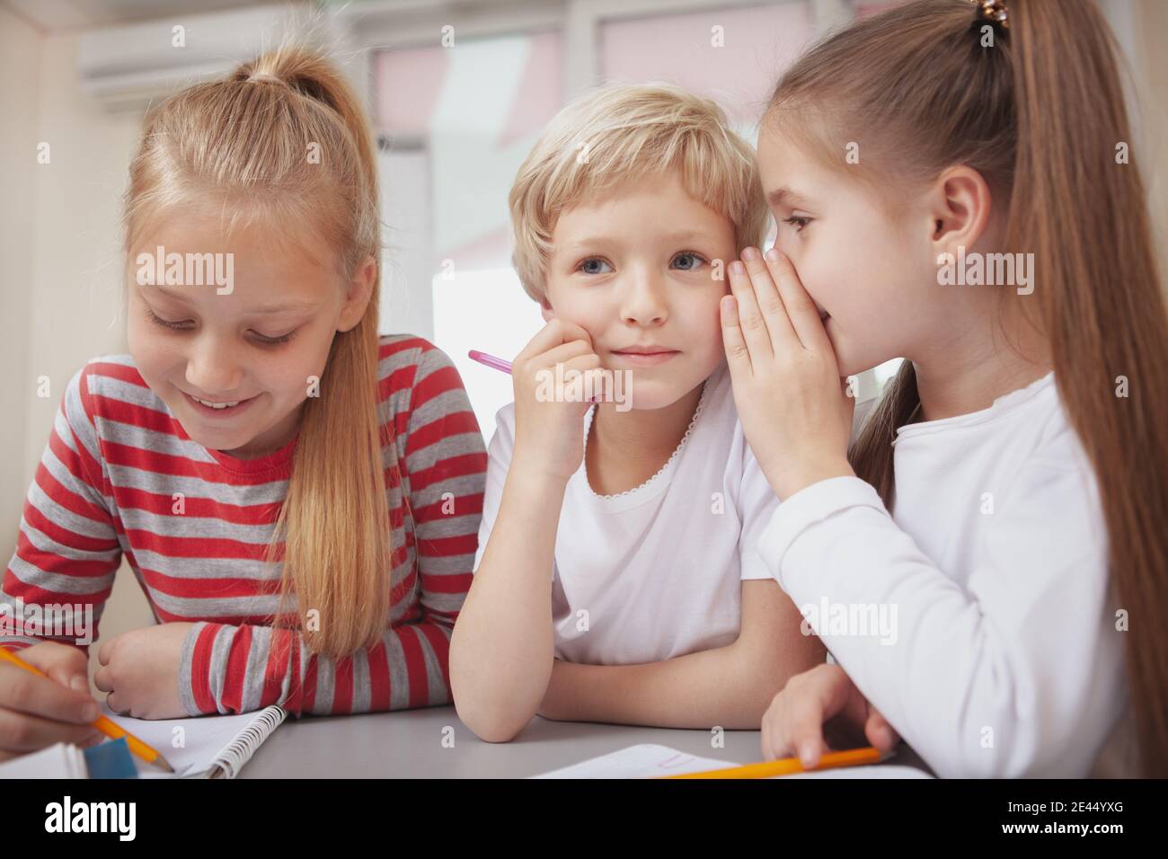 Gossip, bullying, secrets concept. Adorable blond haired little girl ...