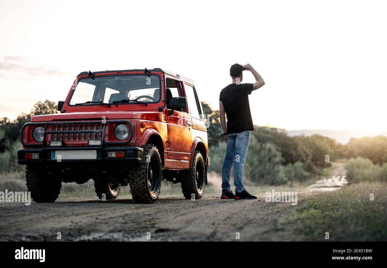 Full body back view of unrecognizable male adventurer standing near red ...