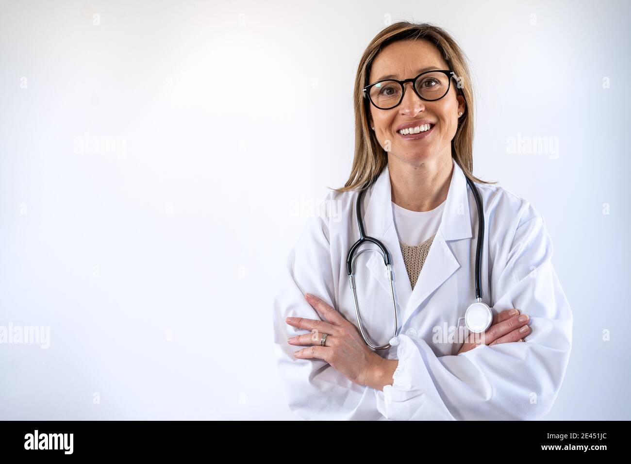 Smiling female medic wearing white uniform standing with stethoscope ...