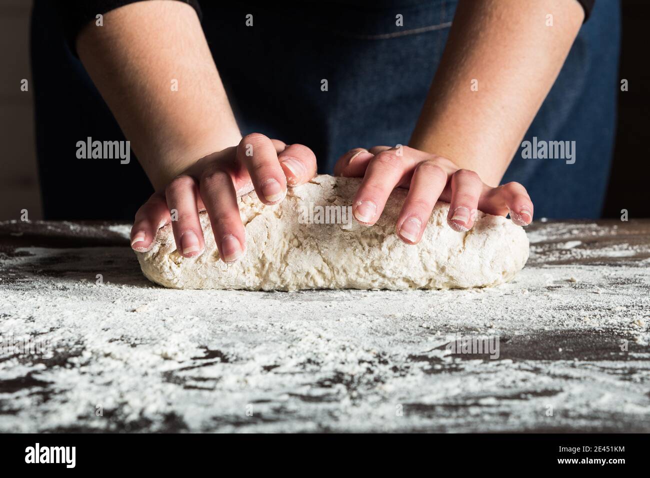 Crop anonymous baker kneading dough on table with flour while preparing ...