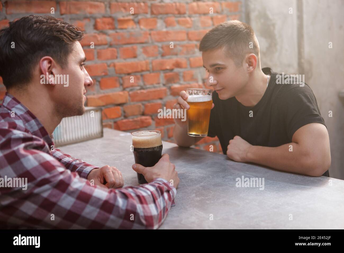 Two male friends drinking beer at the pub together Stock Photo - Alamy
