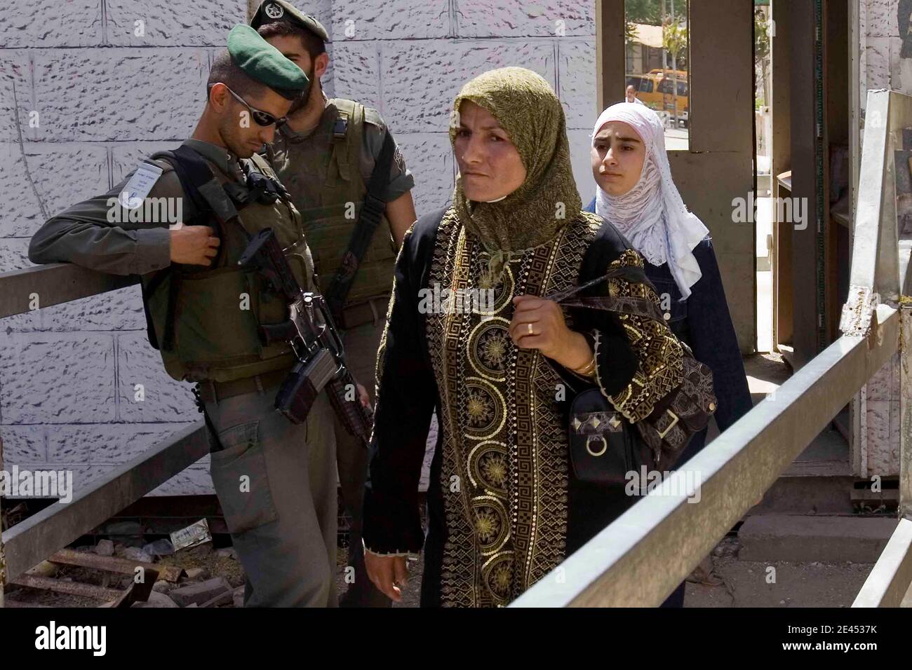 "Palestinian women walk past Israeli border police guards as they cross ...