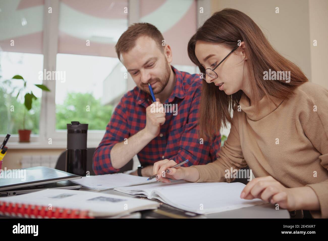 Lovely teenage girl doing assignment with her teacher, copy space ...