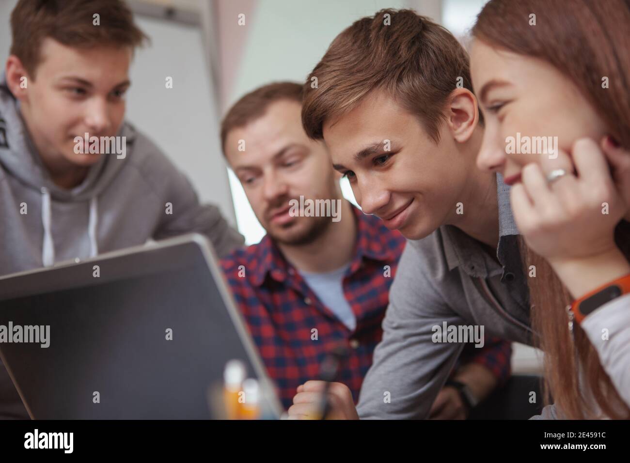 Mature male teacher helping his students in class. Group of teenagers ...