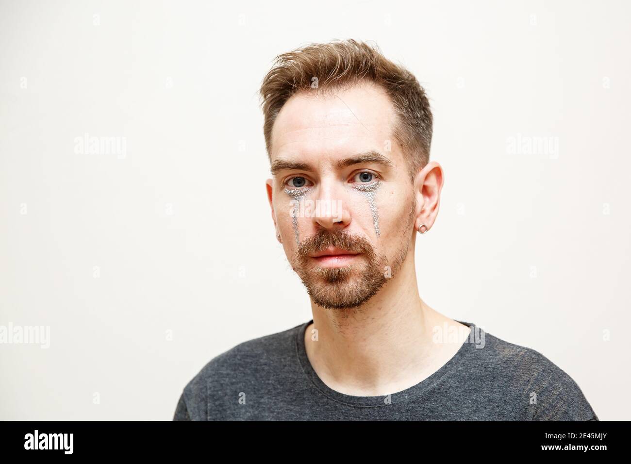 Sad man on a uniform background. Glitter in the form of tears on the ...