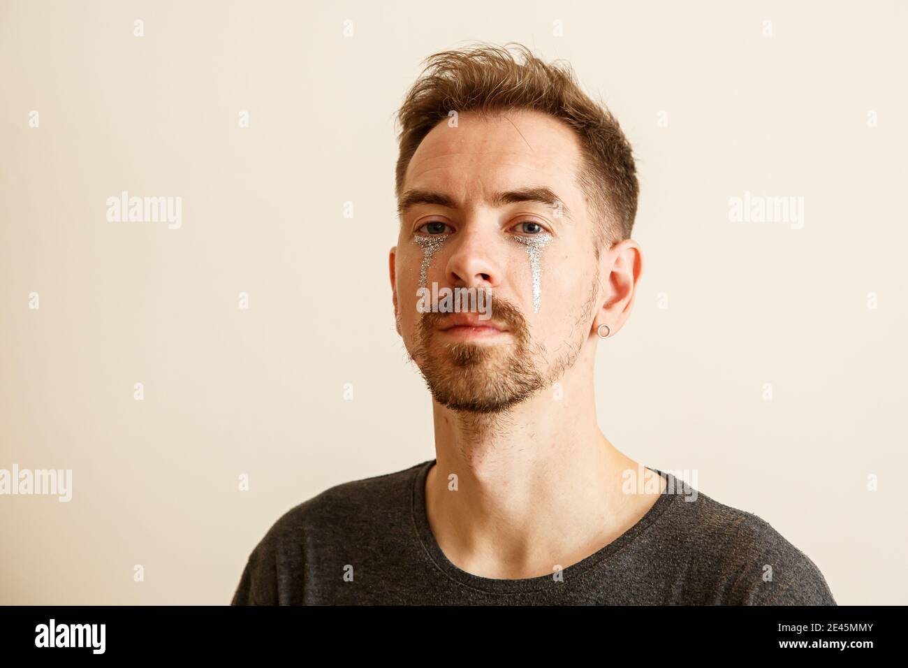 Portrait of a young man with glitter under his eyes Stock Photo - Alamy