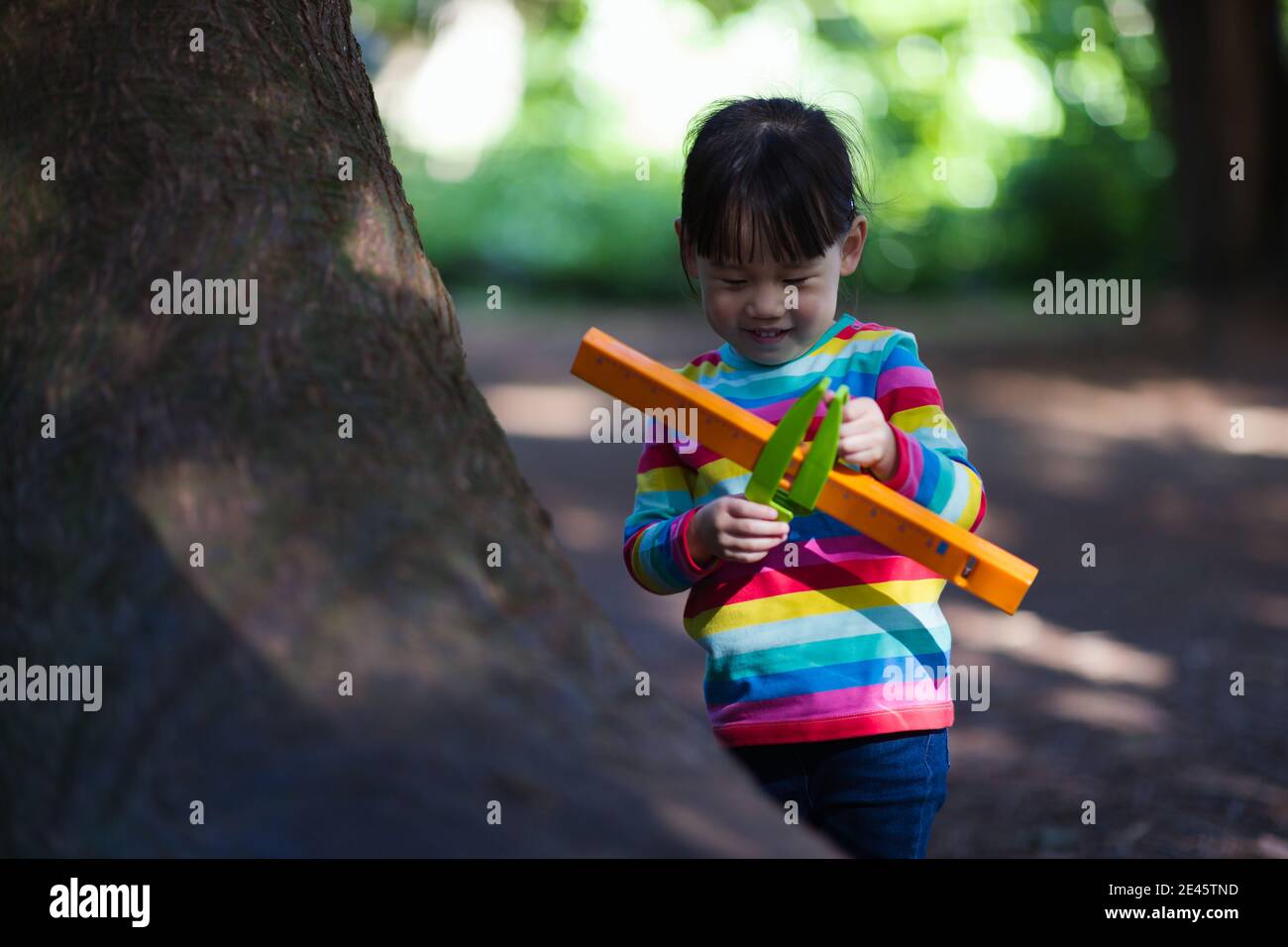 young girl playing outdoor measure-mate in the forest park for leaning ...