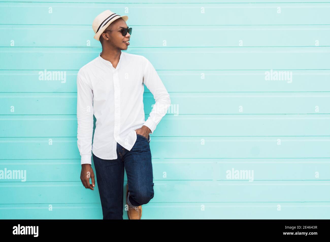 Cool Afro-American male leaning against a light blue background Stock ...