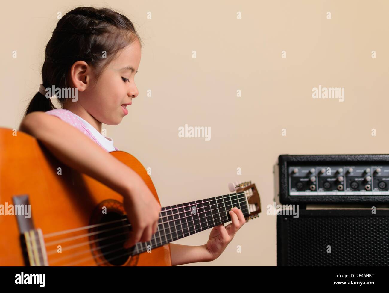 Cute Latin girl practices music on her guitar Stock Photo - Alamy