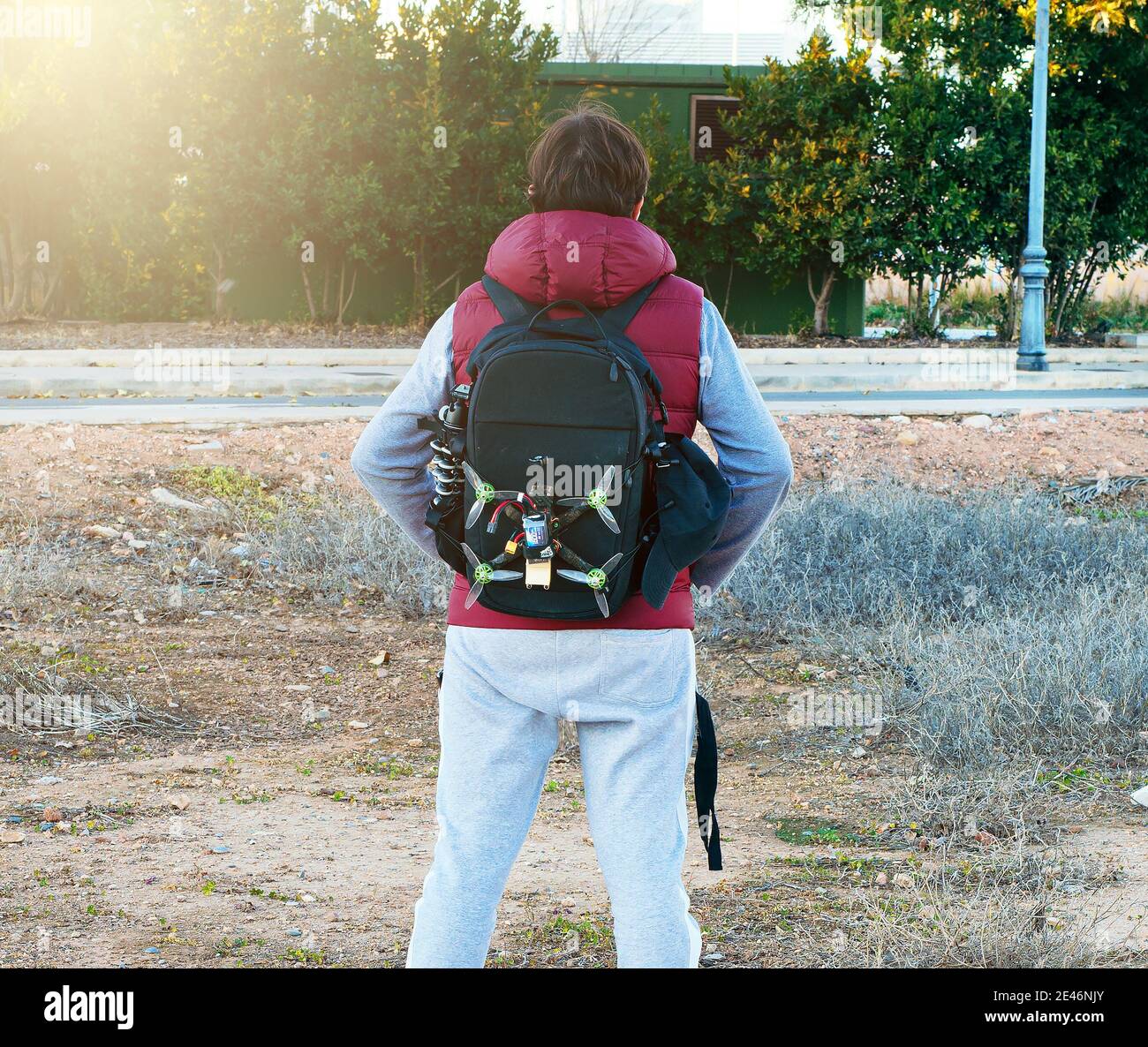 Unrecognizable man wearing a backpack carrying a drone, a tripod and a ...