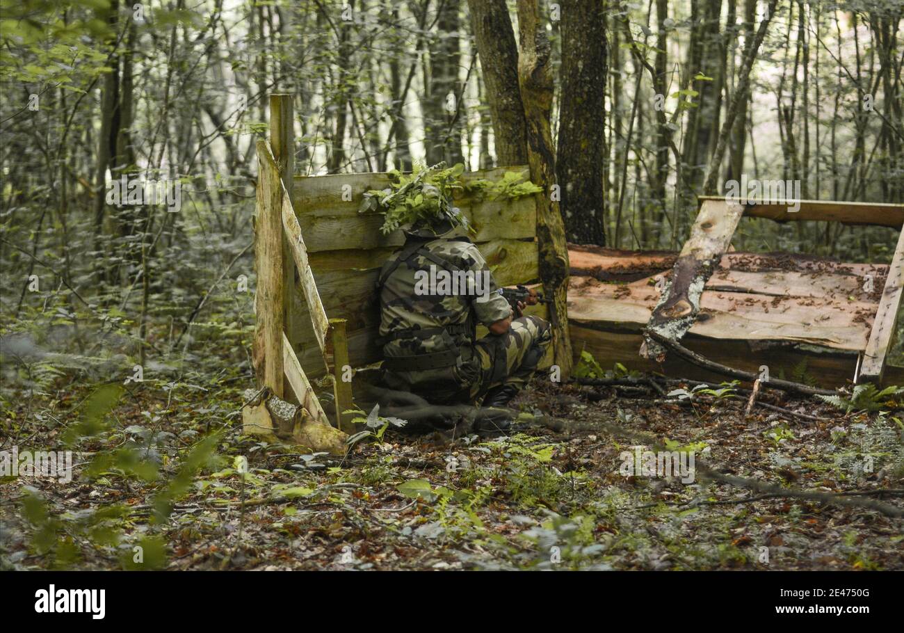 Back view of special forces soldier hiding behind a wooden fence in a ...