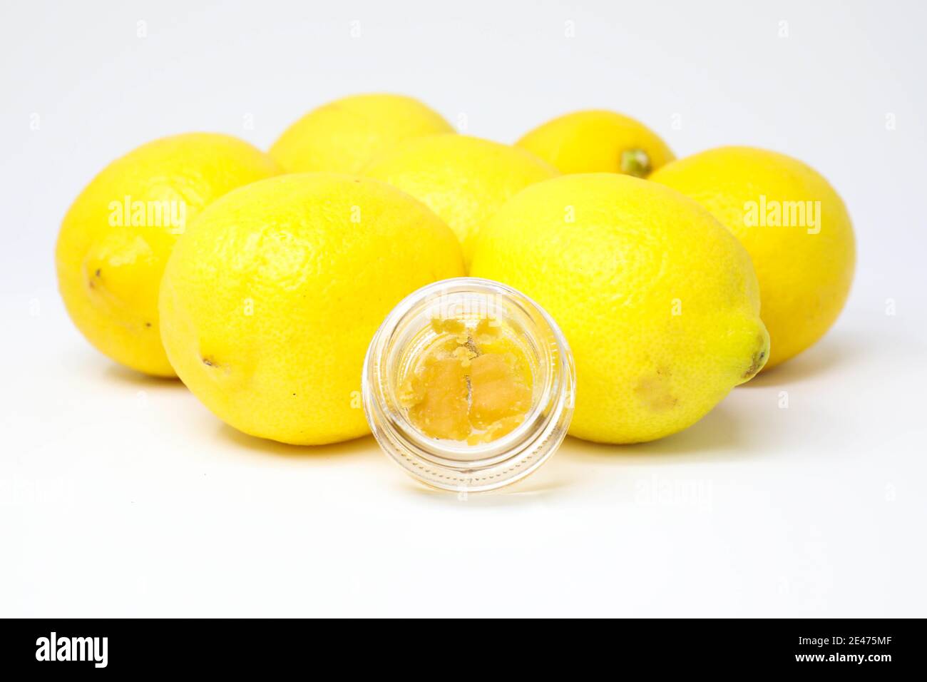 Closeup shot of lemons and a small container of a sample on a white ...