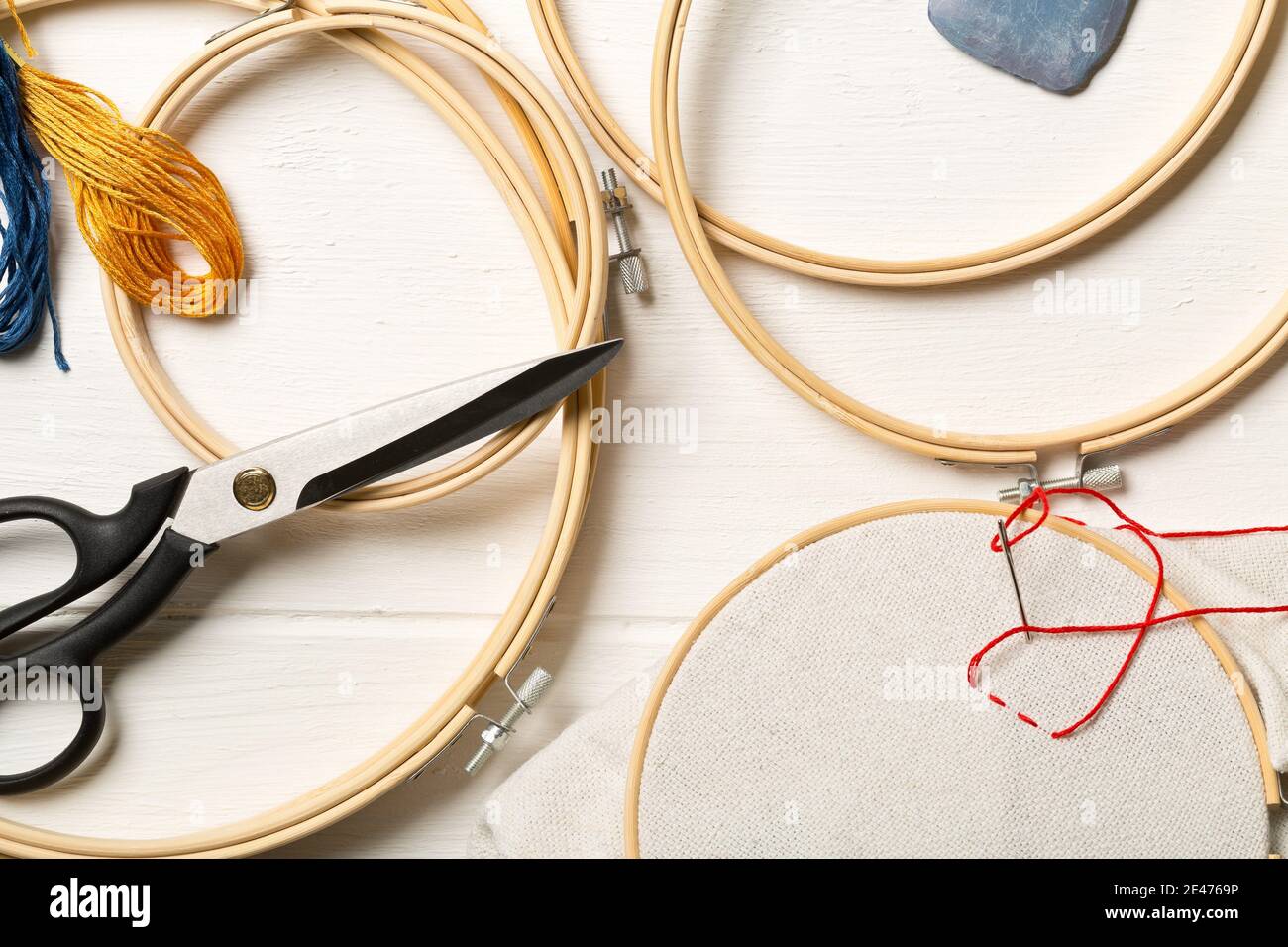 Round stitching or embroidery frame with red stitching and sewing tools ...