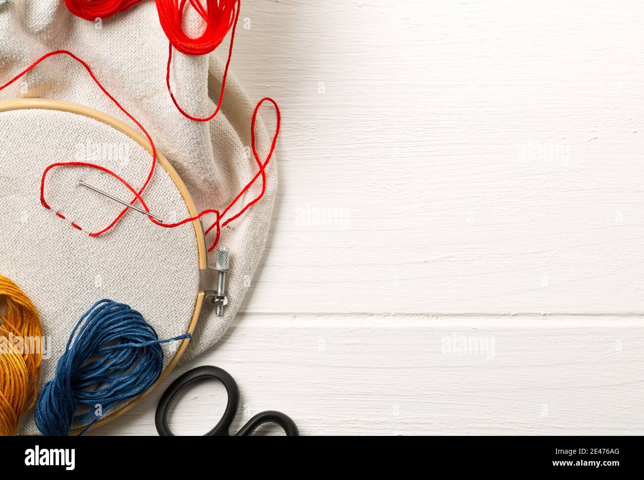 Round stitching or embroidery frame with red stitching and sewing tools ...