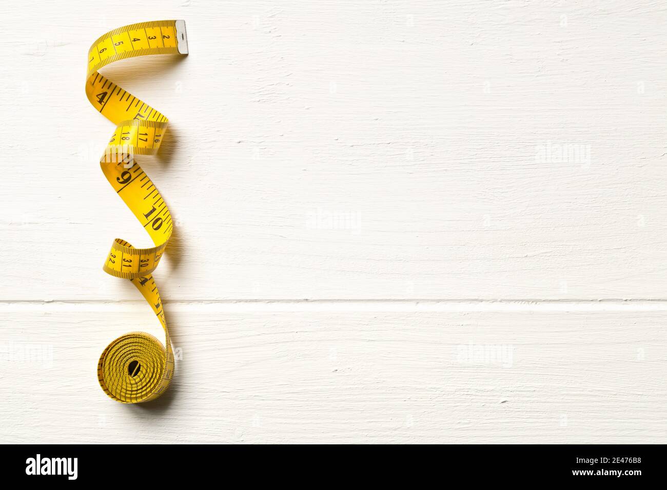 Tape measure sewing tool over white wooden table background with copy ...