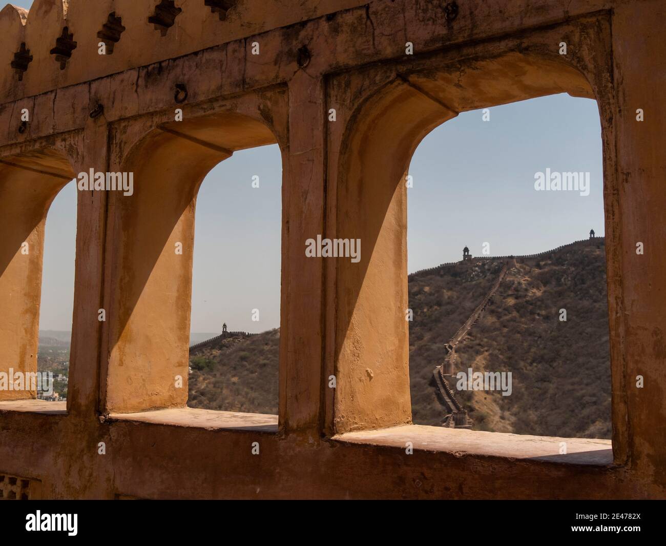 towers and fort walls on a hill frameed amber fort arches in jaipur ...