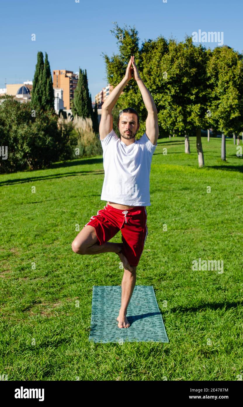 Vertical shot of a Man Keeping Balance on One Leg with Raised Arms ...