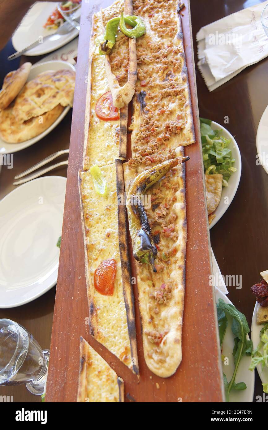 Traditional Turkish pide served on a long wooden plank in a restaurant ...